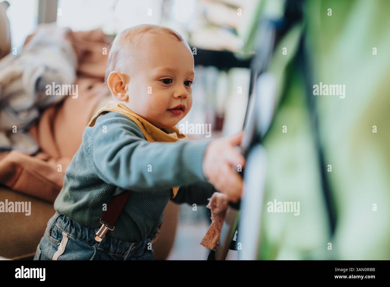 Curious baby exploring a stroller indoors with a playful and content ...