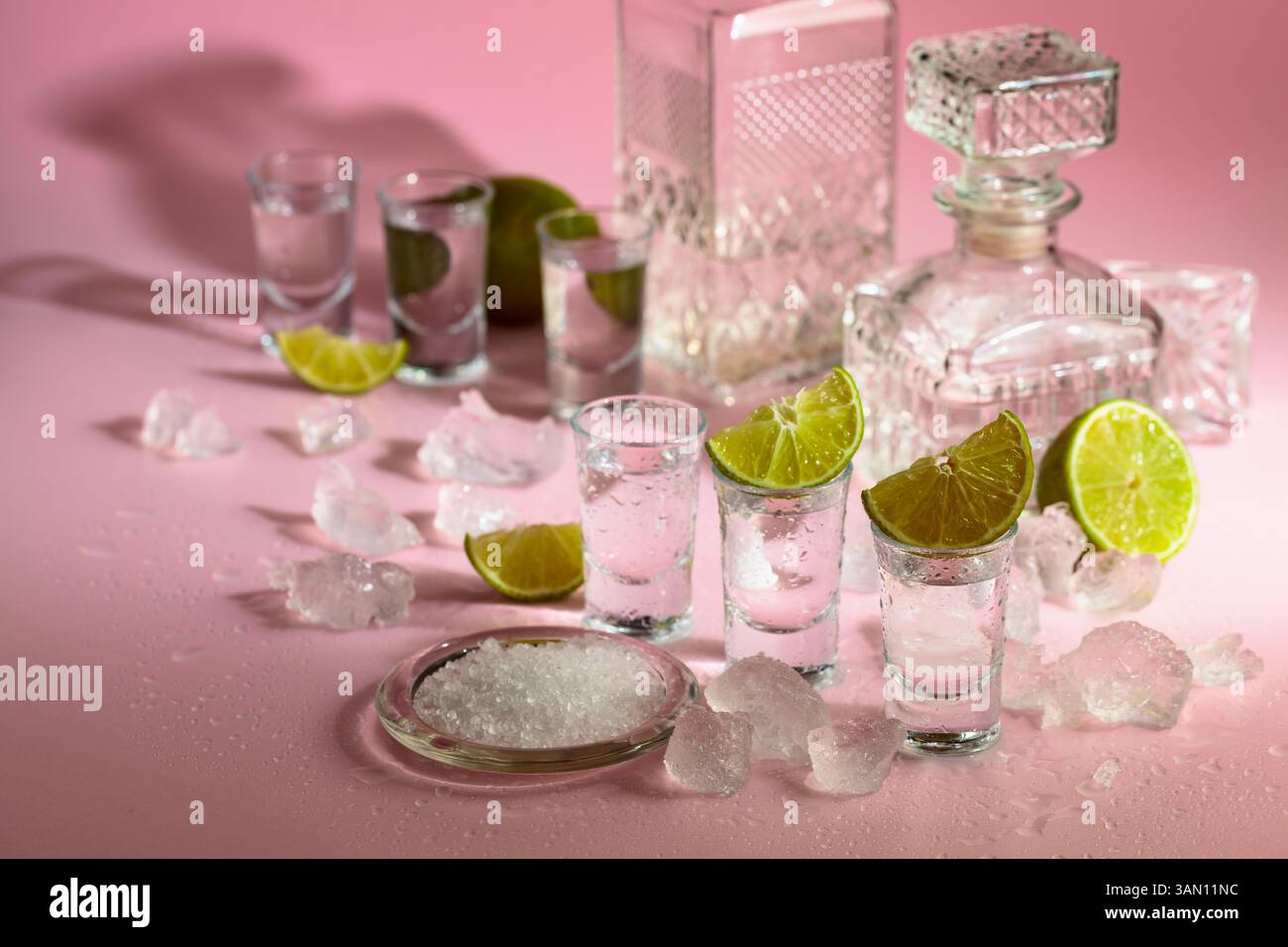 Mexican tequila with lime, sea salt, and crushed ice on a wet pink ...