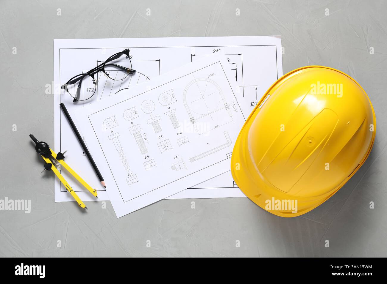 Different engineering drawings, hard hat, pencil, divider and glasses ...