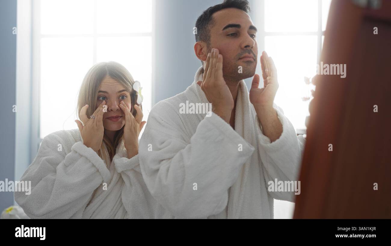 Couple in spa room wearing robes applying skincare product looking at ...