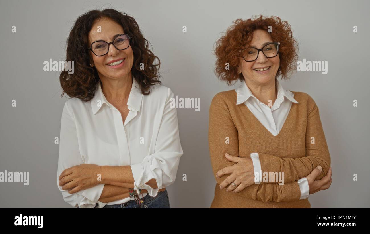 Two middle-aged hispanic women stand together, smiling warmly with arms ...