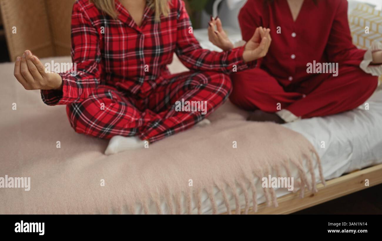 Women in pajamas meditating on bed at home in a cozy bedroom setting ...
