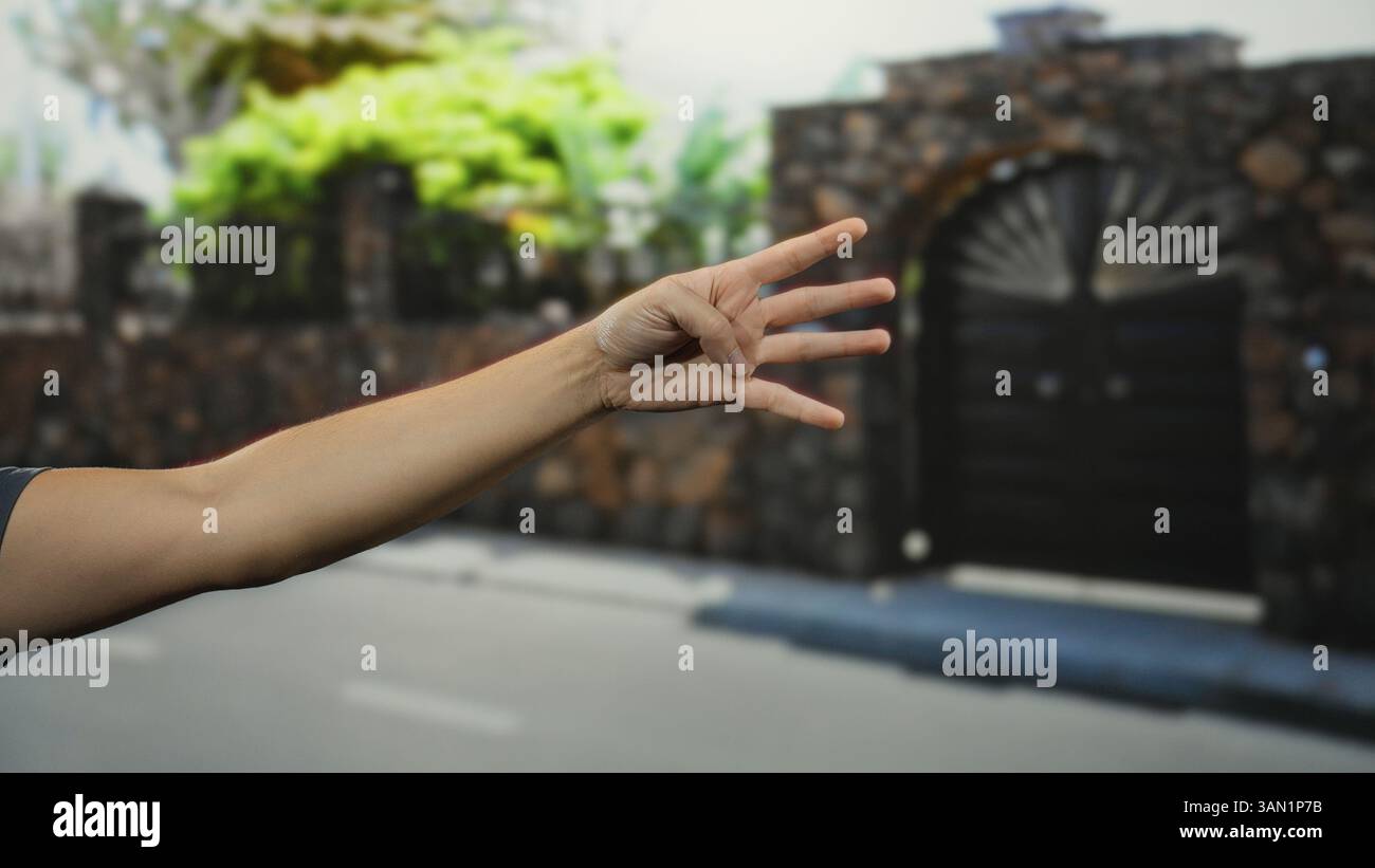 Man extends hand with fingers spread in an outdoor city street ...