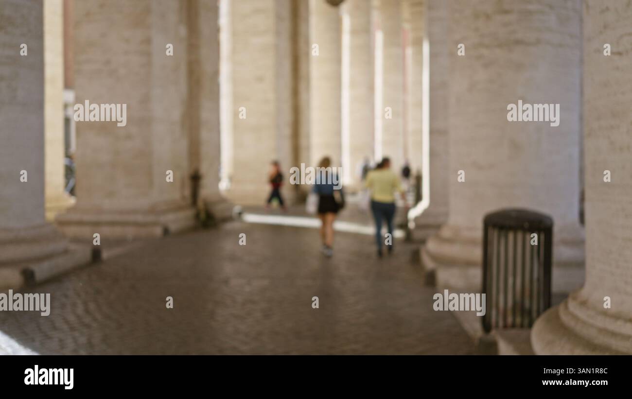 People walking through blurred columns in vatican city under sunlight ...