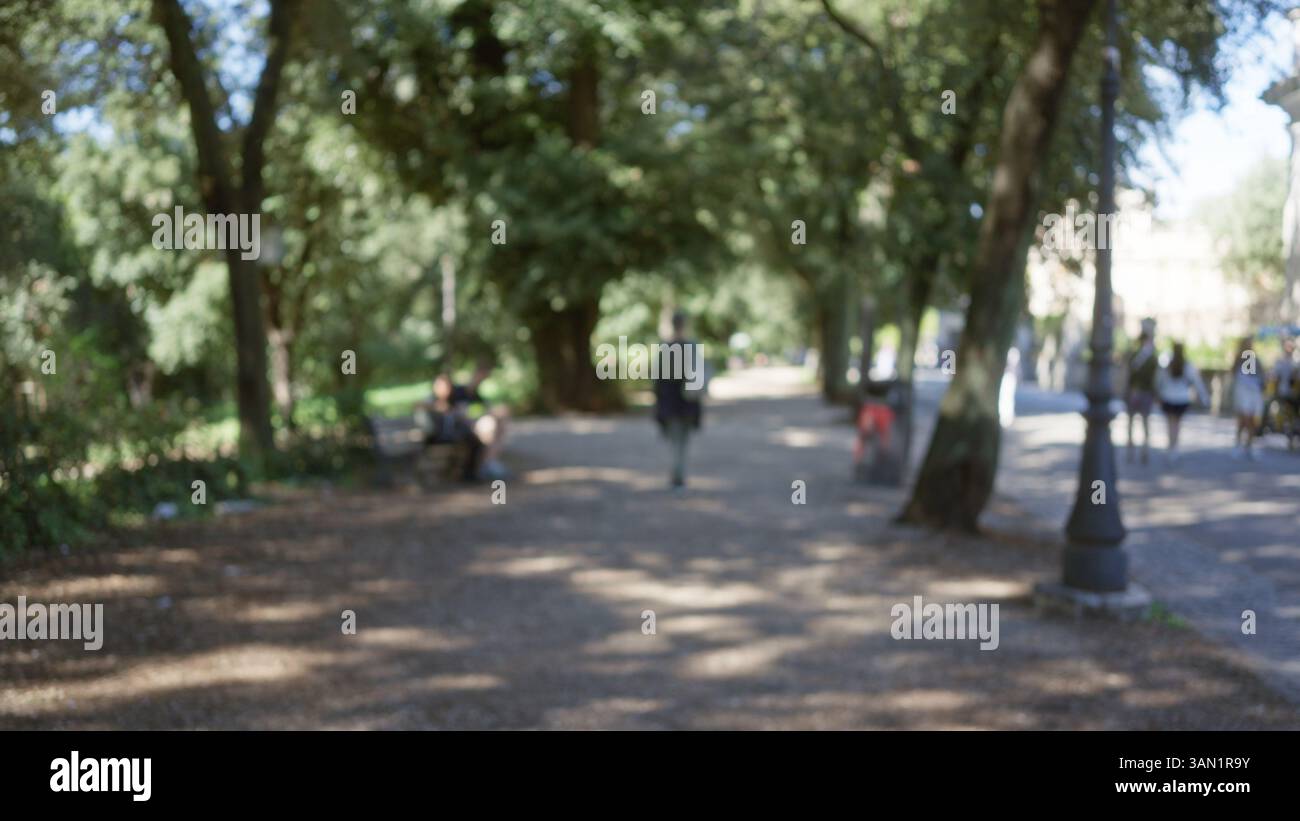 Blurred figures stroll in the serene villa borghese garden in rome ...