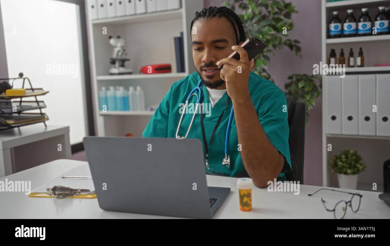 Young man with braids working at laptop in a hospital room, wearing ...