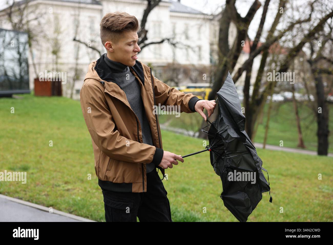 Man with broken umbrella fighting wind under rain outdoors Stock Photo ...