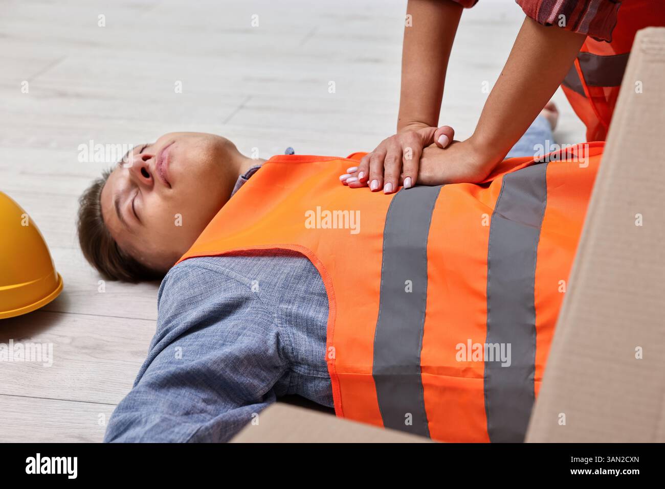 Accident at work. Woman performing CPR on her unconscious colleague in warehouse, closeup Stock ...