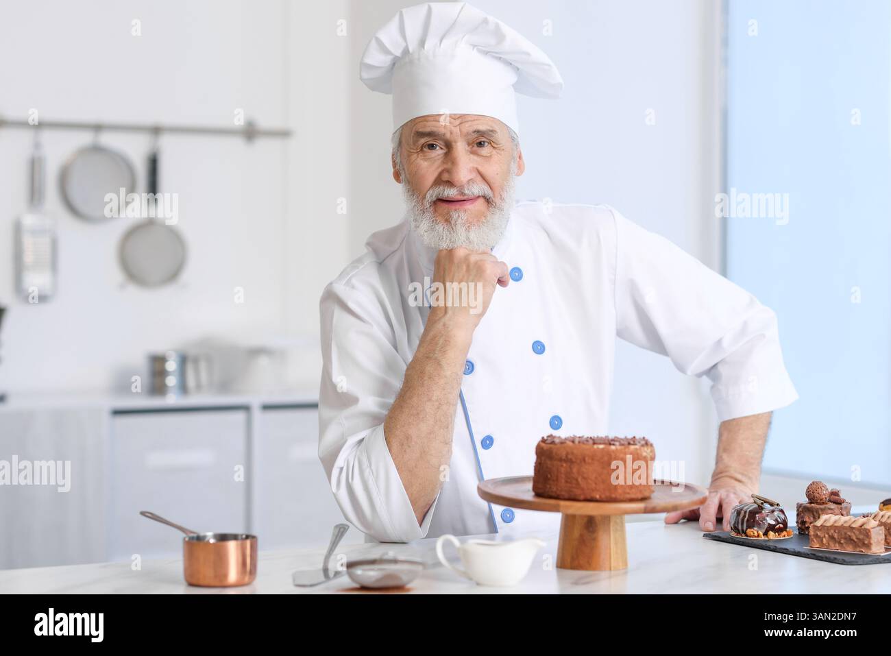 Elderly pastry chef at table with desserts in kitchen Stock Photo - Alamy