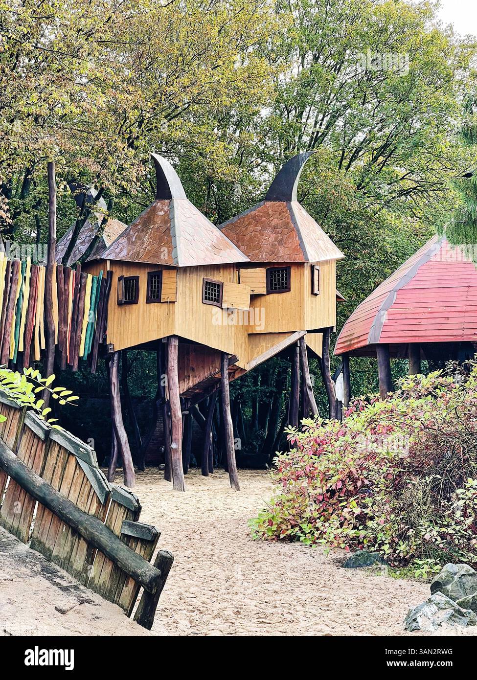 Enchanting elevated wooden playhouse with twin peaked roofs and quirky ...