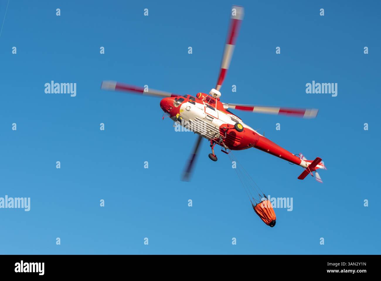 Red helicopter flying above with empty Bambi bucket Stock Photo - Alamy