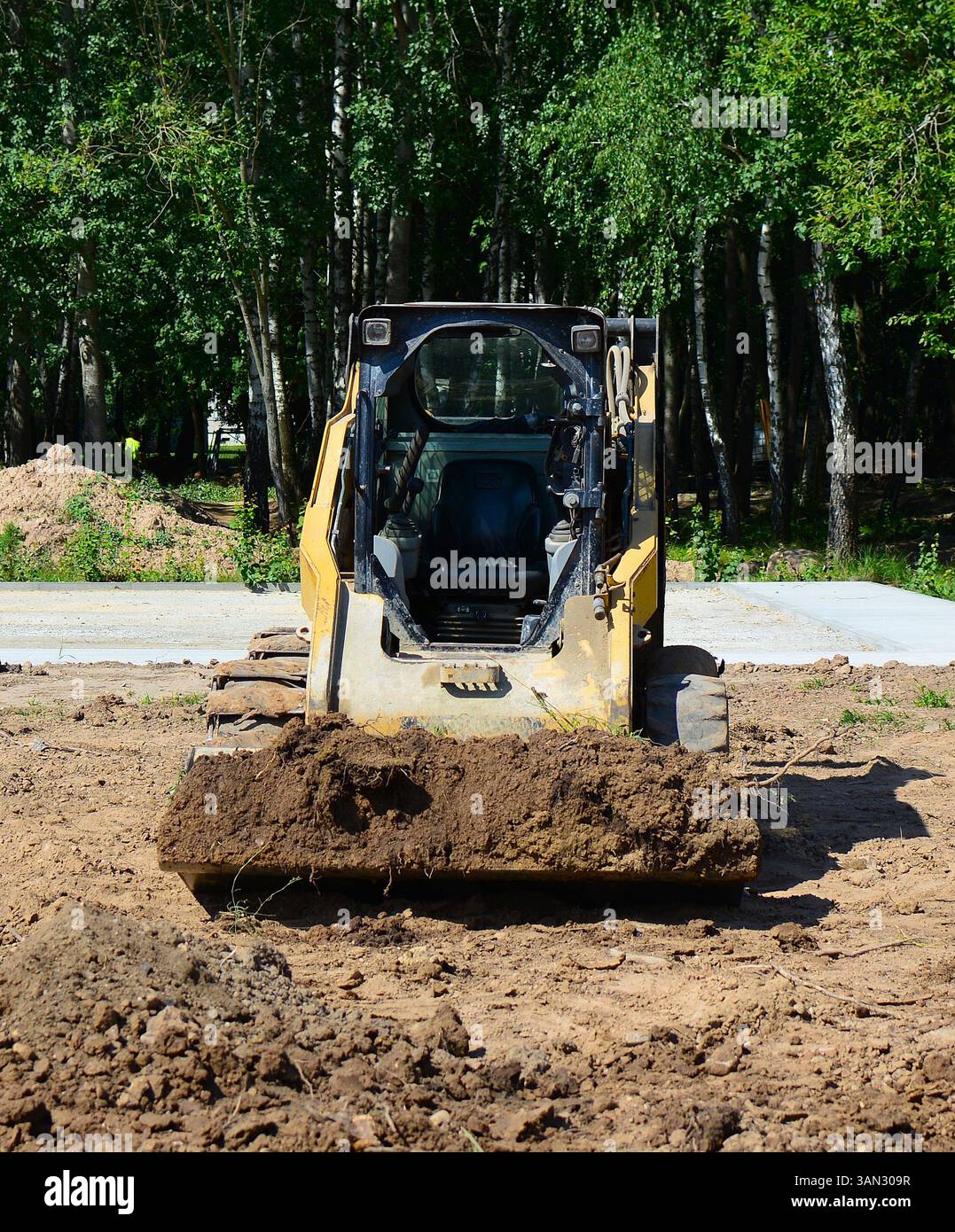 Mini excavator digging and pushing ground in construction site near ...