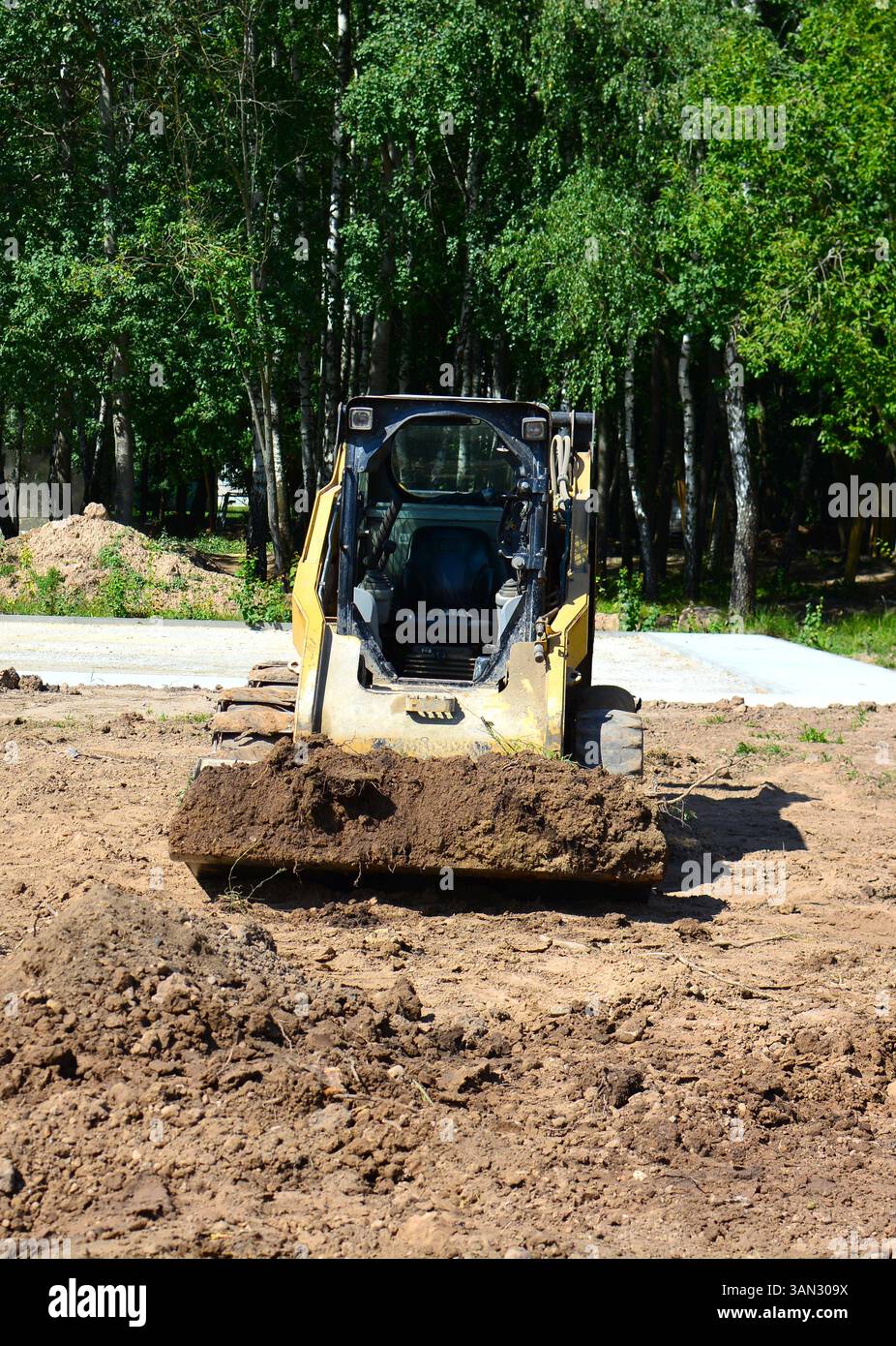 Mini excavator digging and pushing ground in construction site near ...