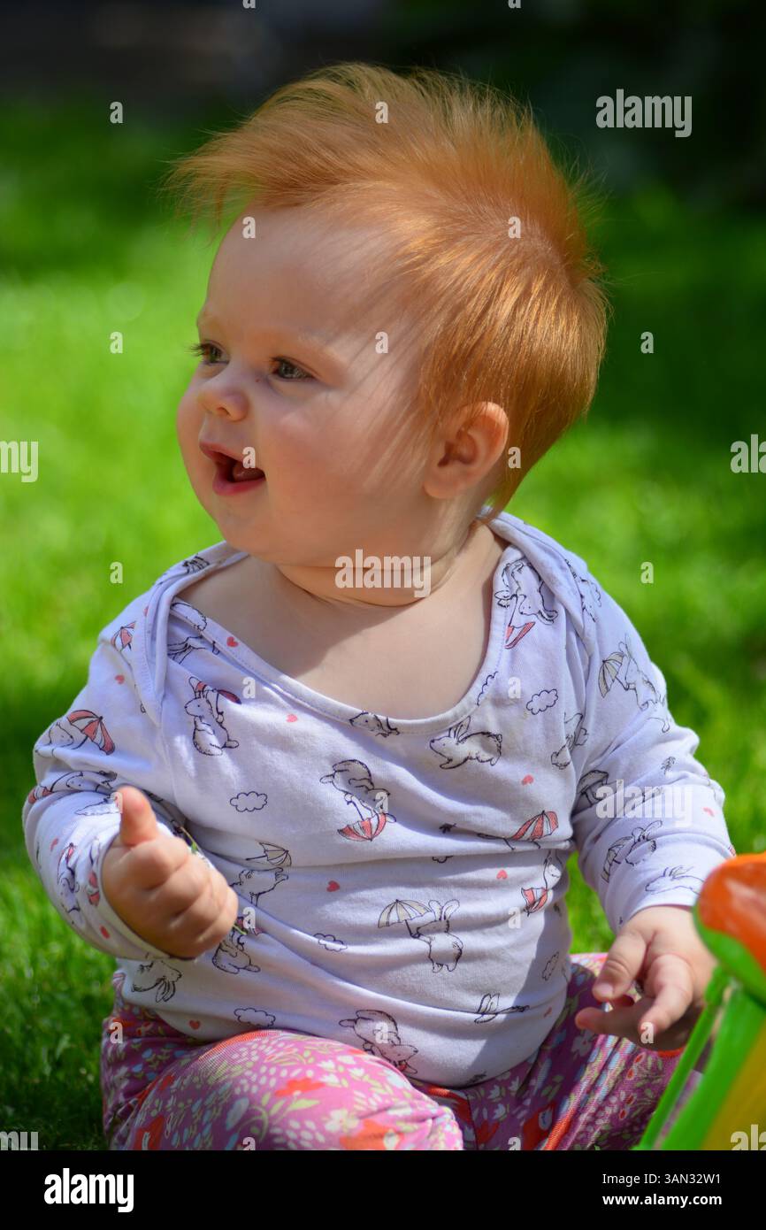 Red hair baby girl smiling with open mouth in a back yard . Toddler ...