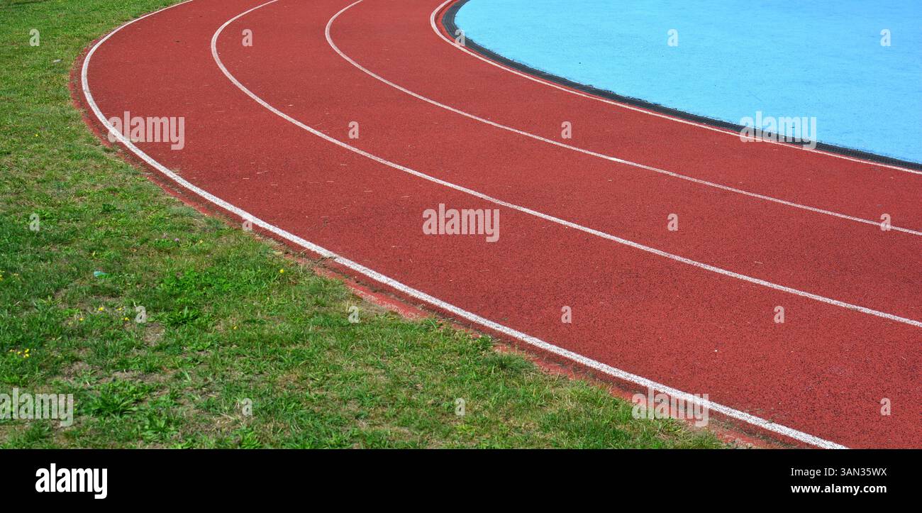 Red running track curve with blue sports field in right side and green ...