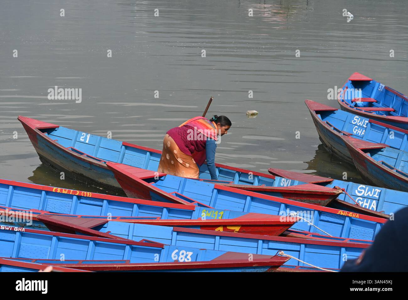 A woman on a colorful boat on lake Phewa, the second largest lake in ...