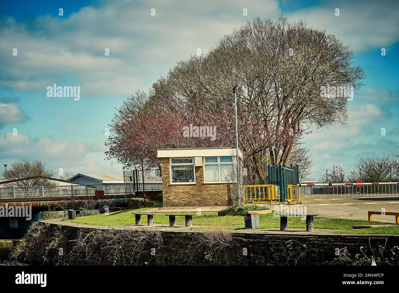 Factory gatehouse with barrier and spring trees Stock Photo - Alamy