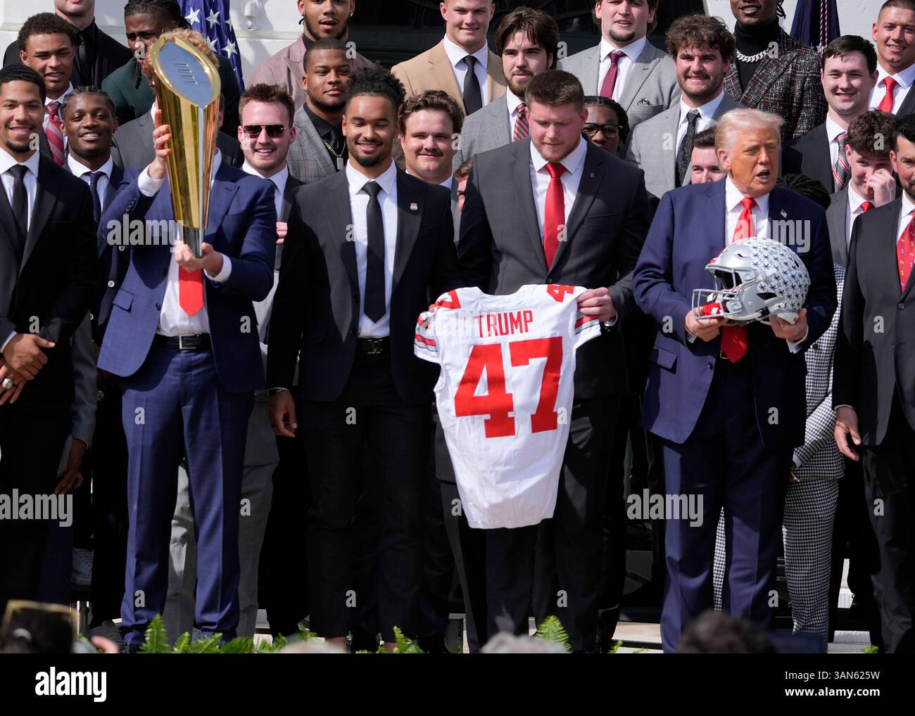President Donald Trump, right, speaks while holding a helmet and ...