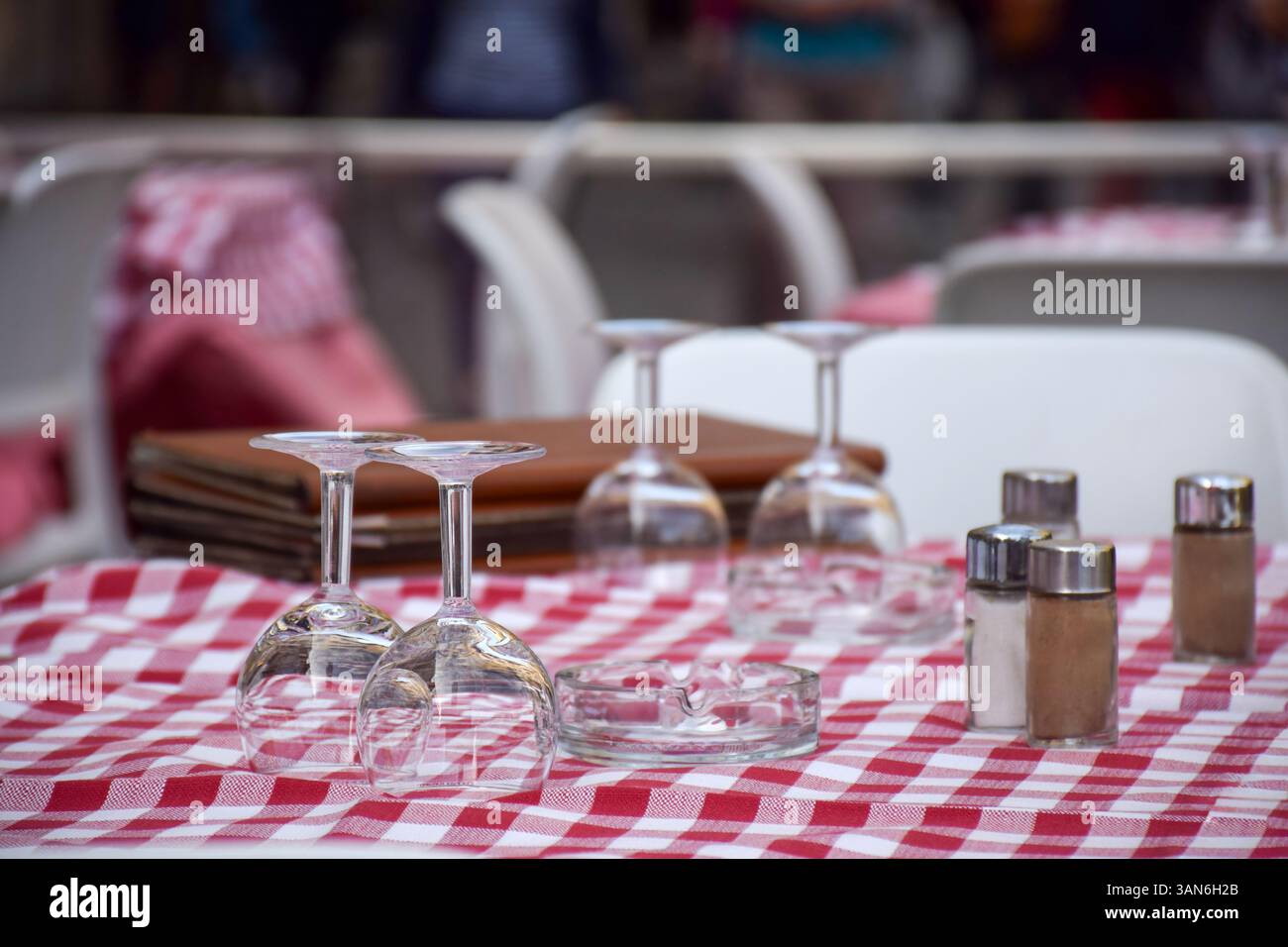 Outdoor restaurant patio table set with red checkered table cloth and ...