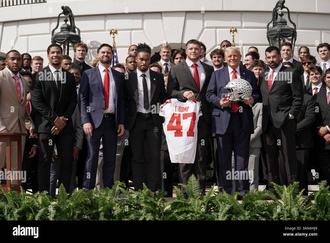 President Trump holds a helmet gifted to him by the 2025 College ...