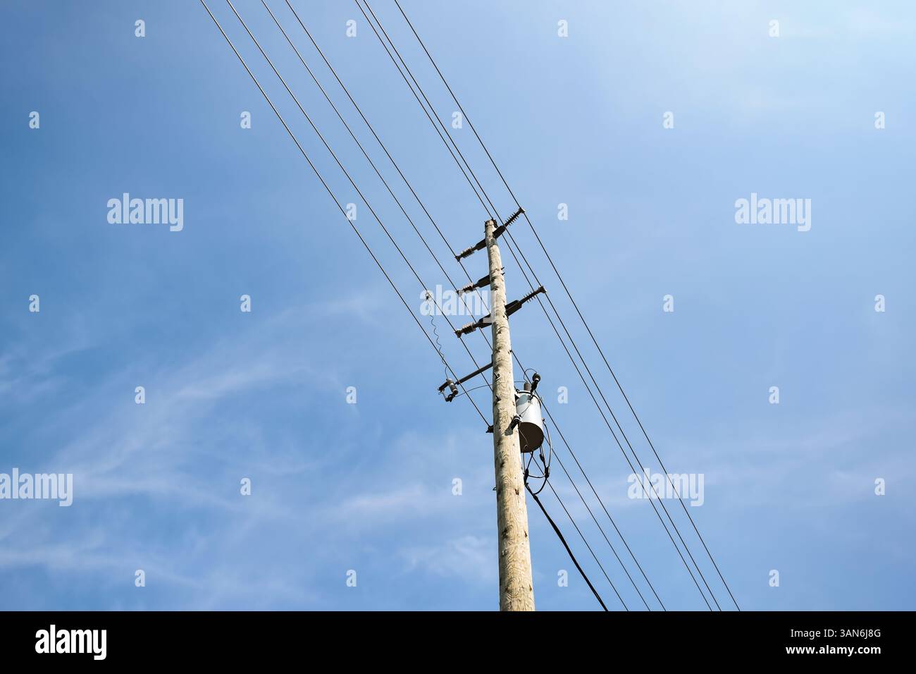 Looking up at hydro electricity pole against blue sky with copy space ...
