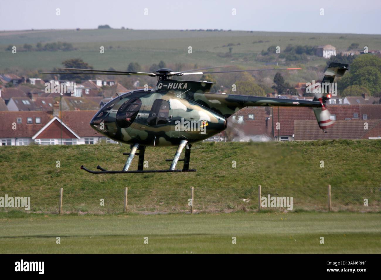 A Hughes 369 helicopter in a camouflage colour scheme departs Brighton ...