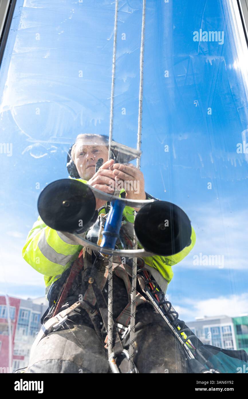 Professional Window Cleaner Working at Height with Safety Gear Ensuring ...