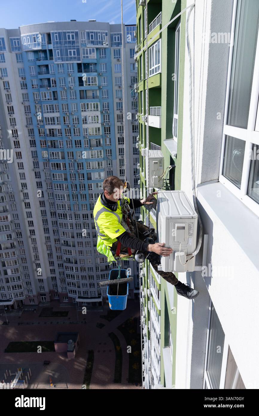 A Brave Worker Maintains Air Conditioning Units on a High-Rise Building ...