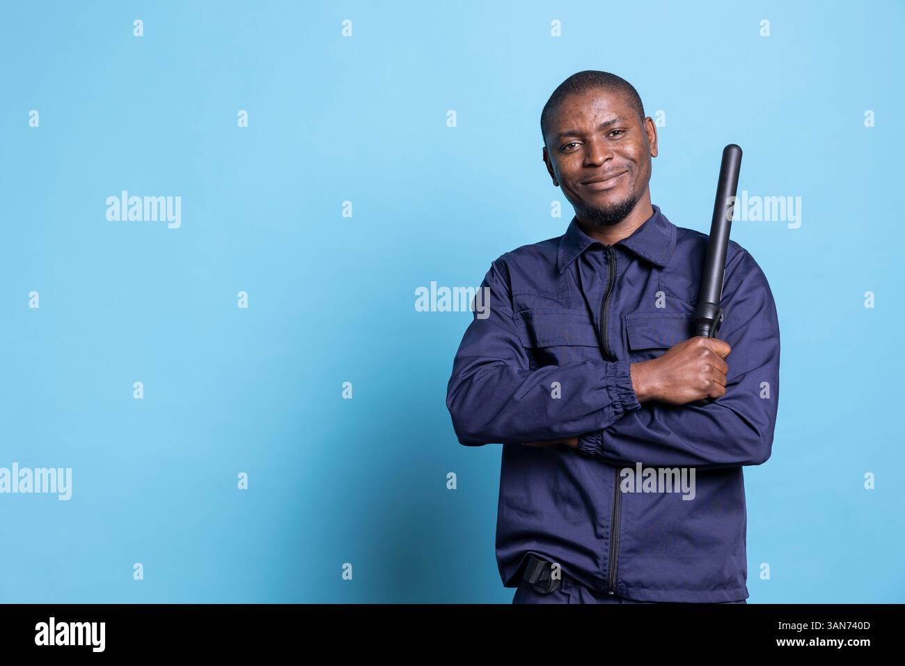 African american bodyguard posing with a baton and uniform in studio ...