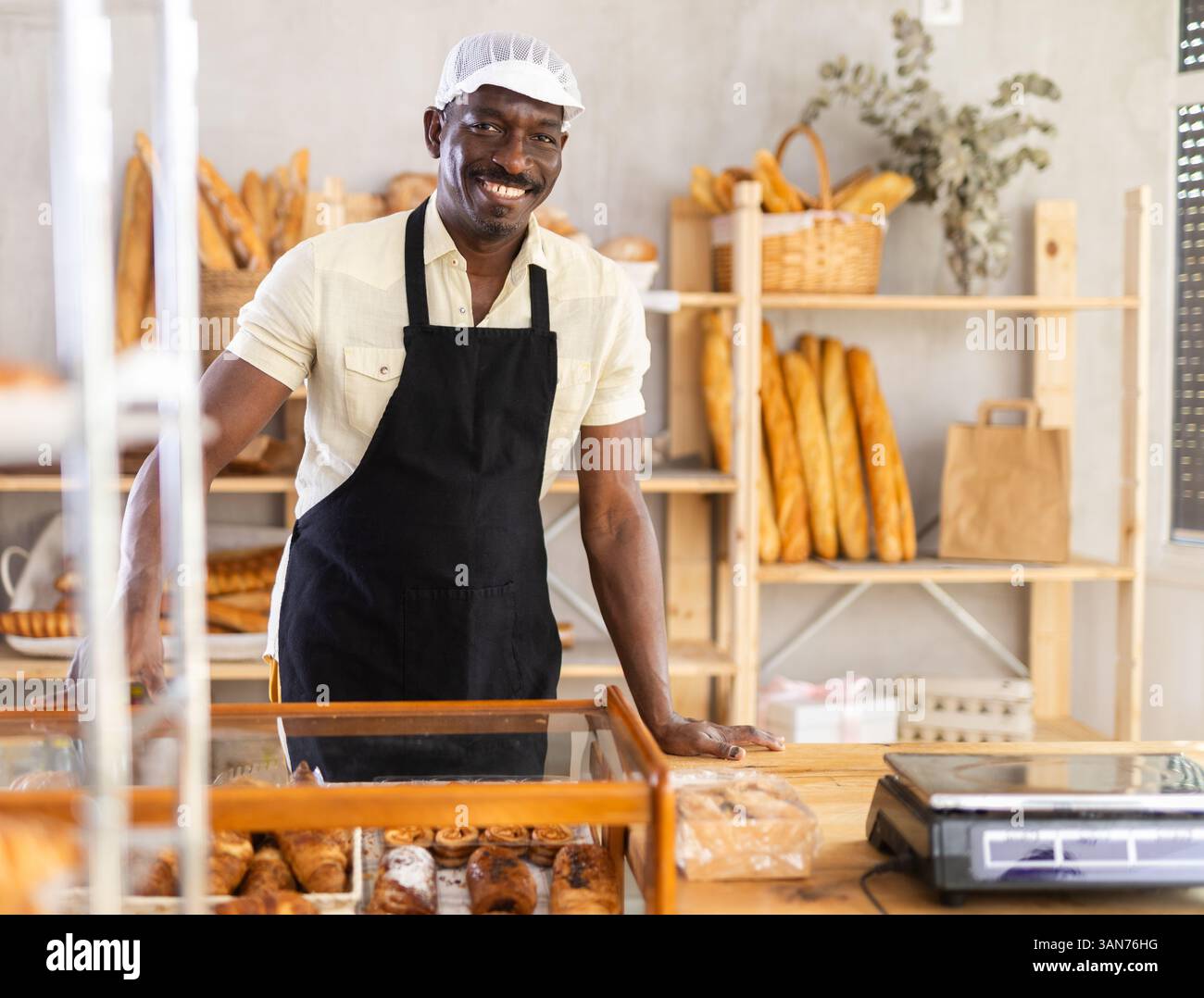 Positive man baker standing at counter in bakehouse Stock Photo - Alamy