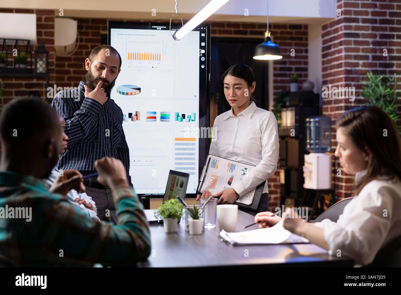 Business team reviews marketing strategies using digital charts on LED ...