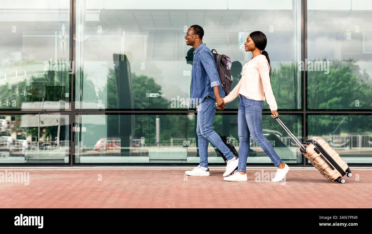Ready for travel. Happy black couple walking with suitcases near ...