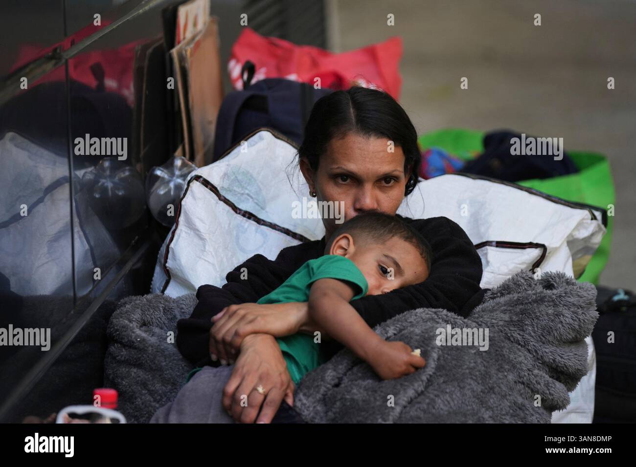 A Venezuelan migrant and her child wait for information about flights ...
