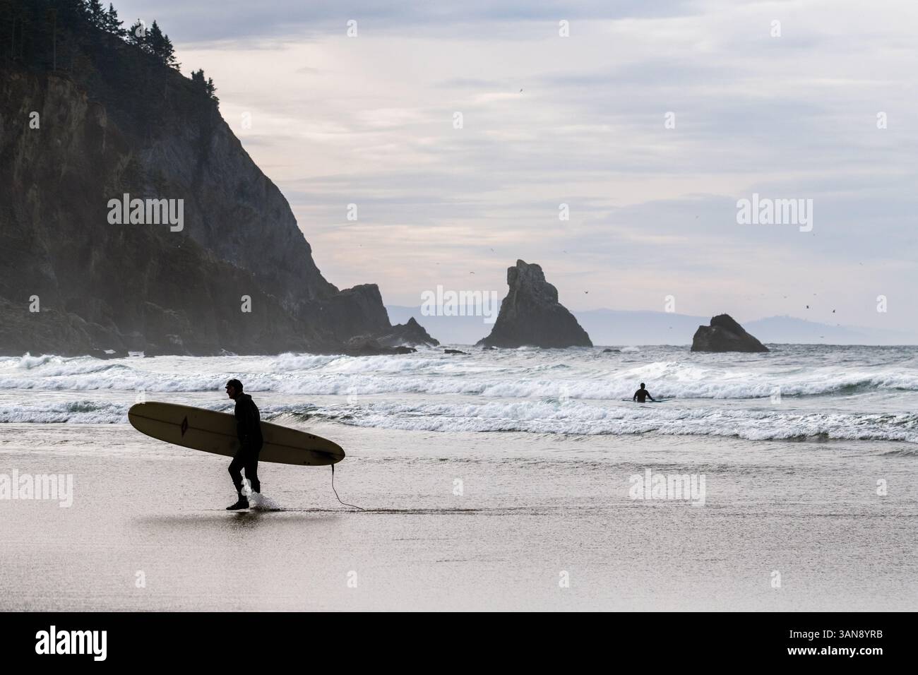 A surfer is riding a wave in the ocean. The sky is cloudy and the water ...