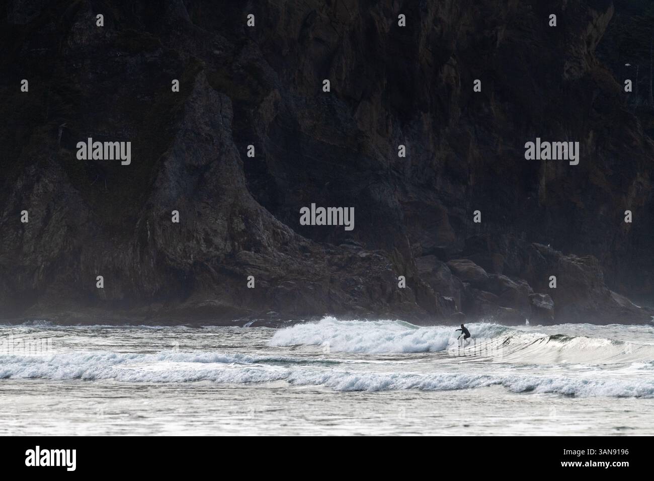 A surfer is riding a wave in the ocean. The sky is cloudy and the water ...