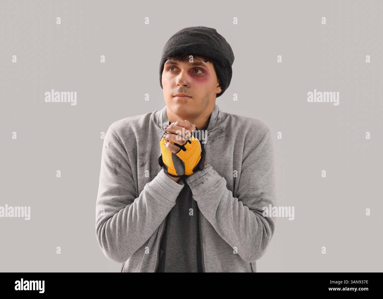 Frozen young homeless man on light background Stock Photo - Alamy