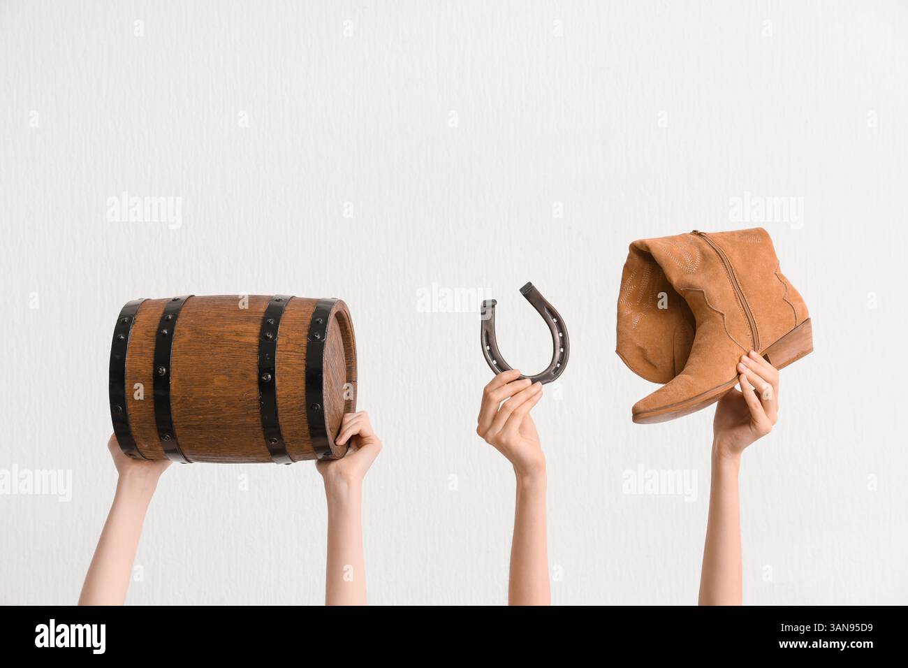 Female hands with wooden barrel, horseshoe and cowboy shoe on light ...