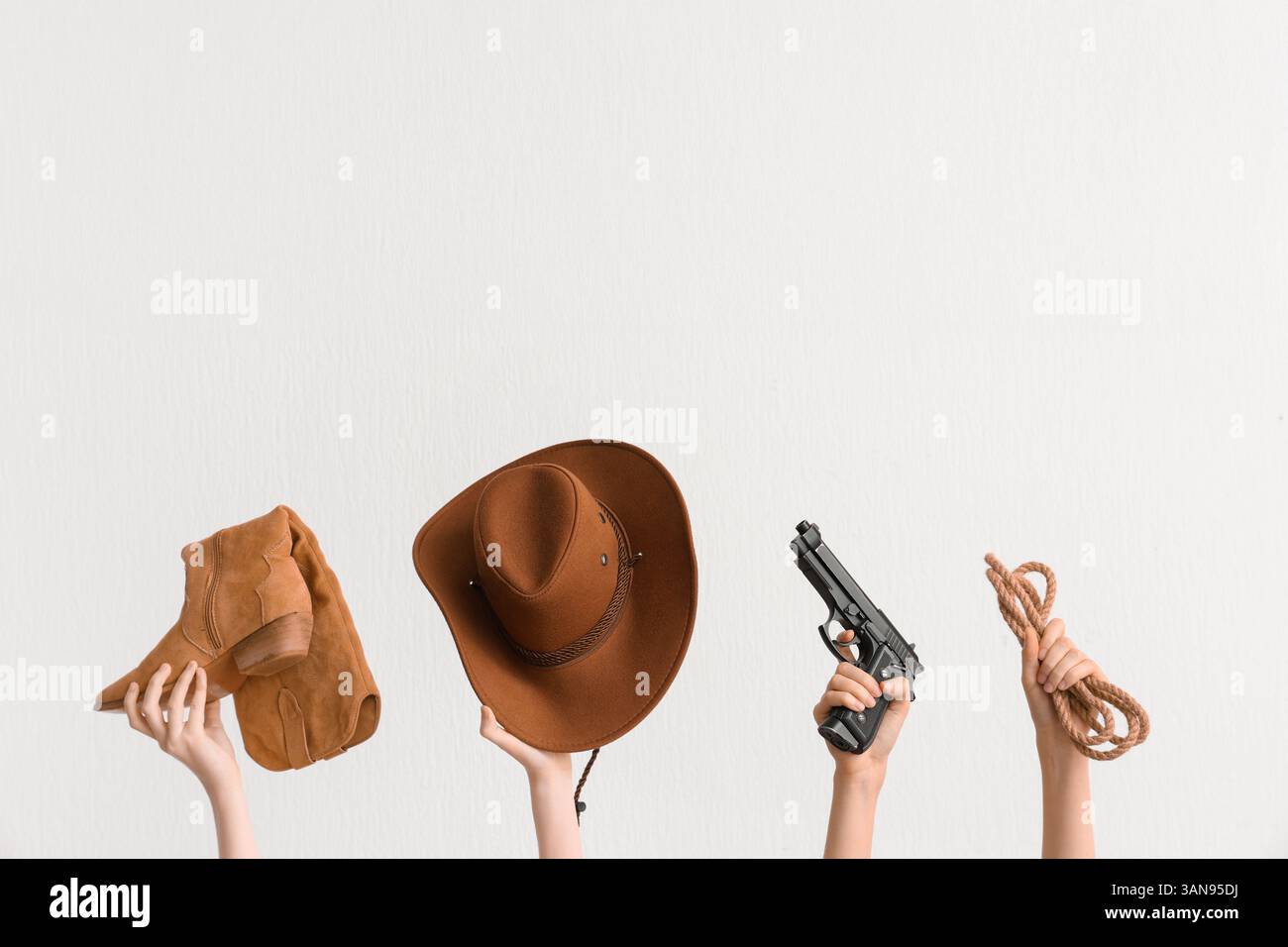 Female hands with cowboy hat, shoe, lasso and gun on light background ...