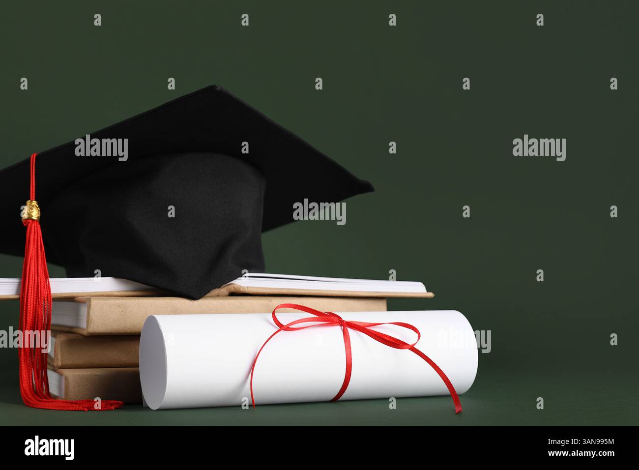 Graduation hat, books and diploma on green background Stock Photo - Alamy