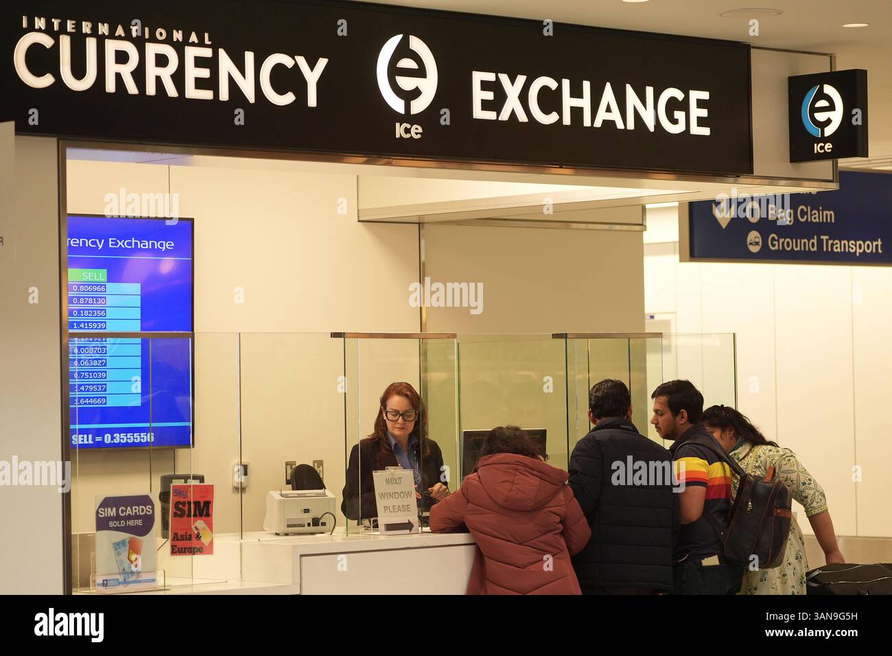 Travelers stand at the window of an ICE International Currency Exchange ...