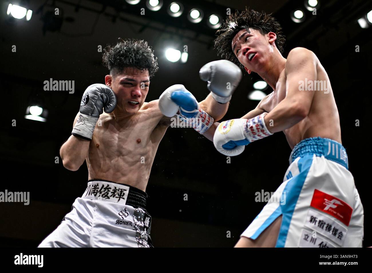 Champion Toshiki Kawamitsu (silver gloves) hits challenger Kyosuke Takami (white gloves) in the ...