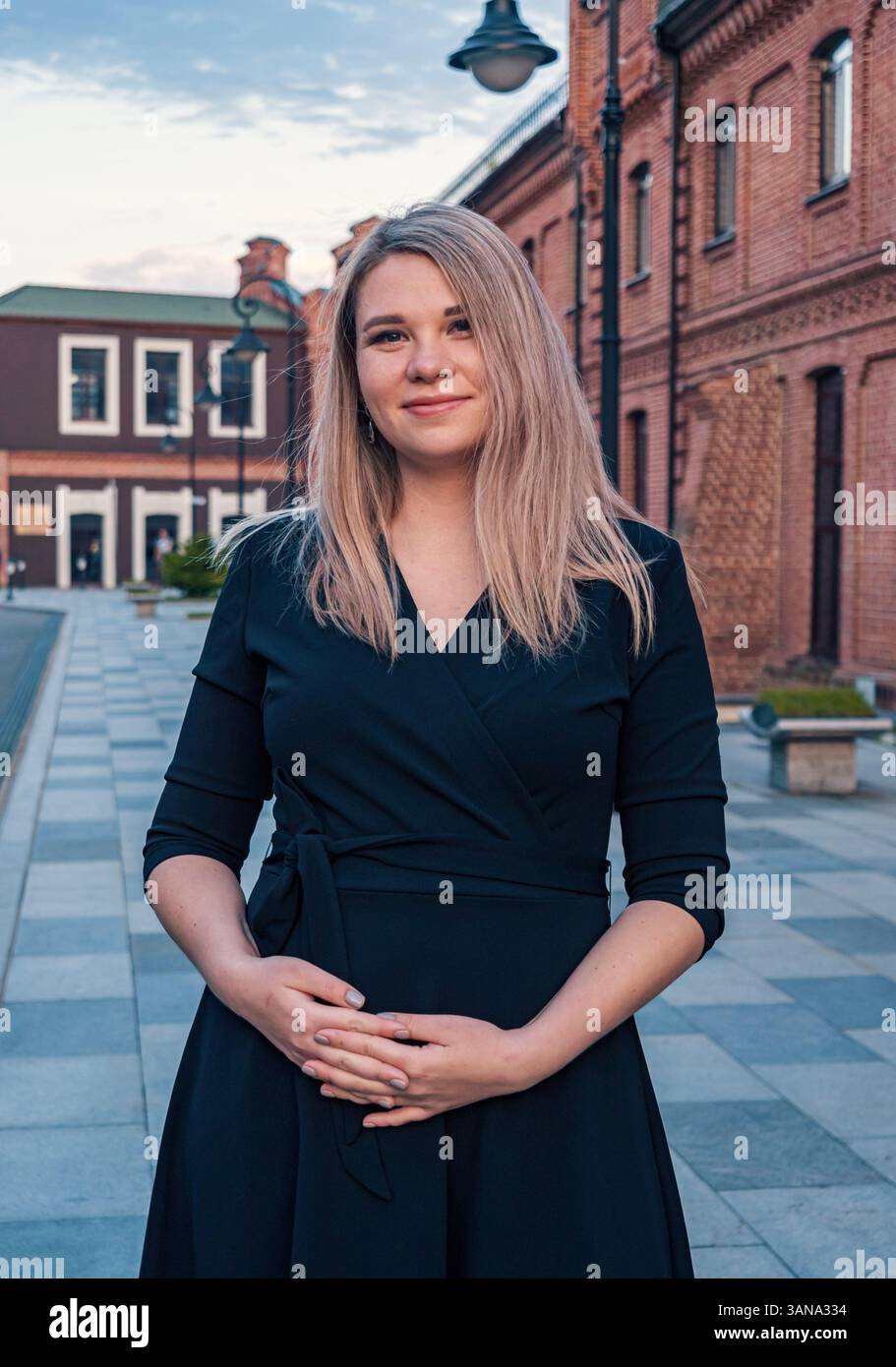 Young pregnant woman in a black dress poses confidently outside ...