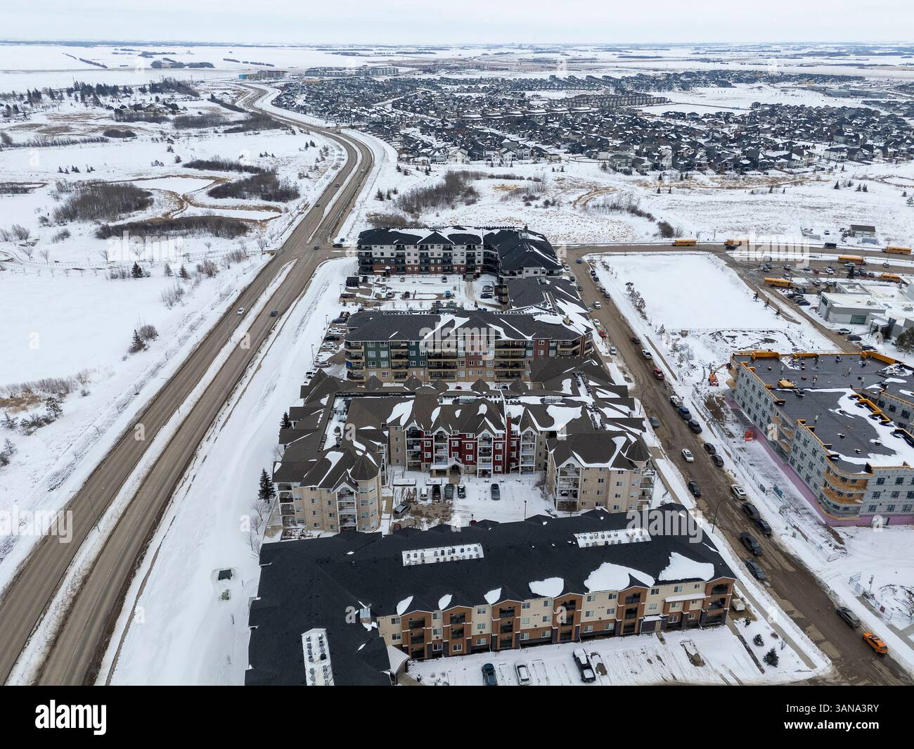 Snowy cityscape with a road and a few buildings. The buildings are ...