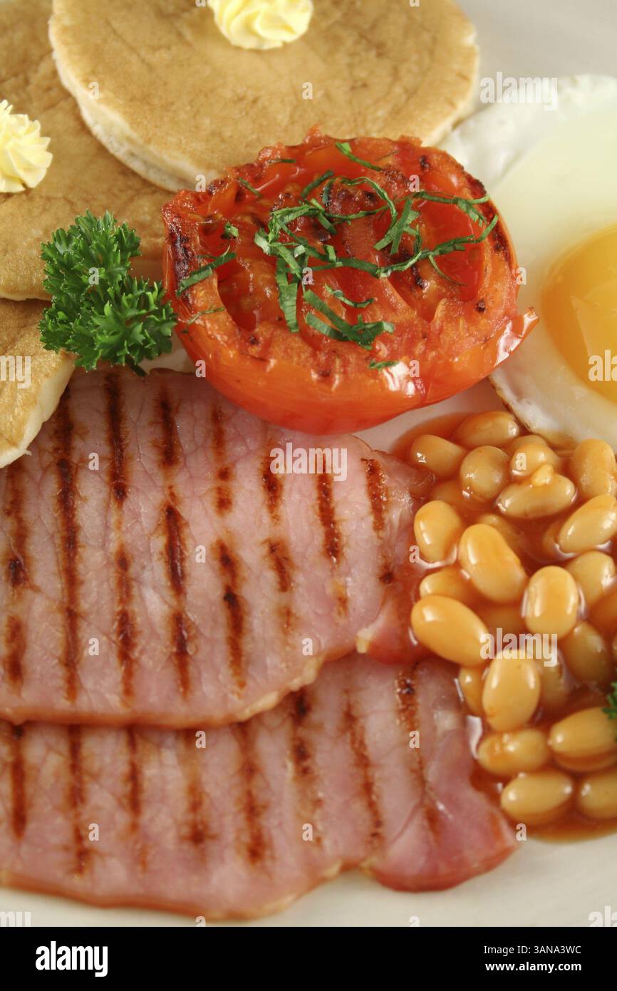 Breakfast of grilled bacon, tomato, egg, baked beans and pancakes Stock ...
