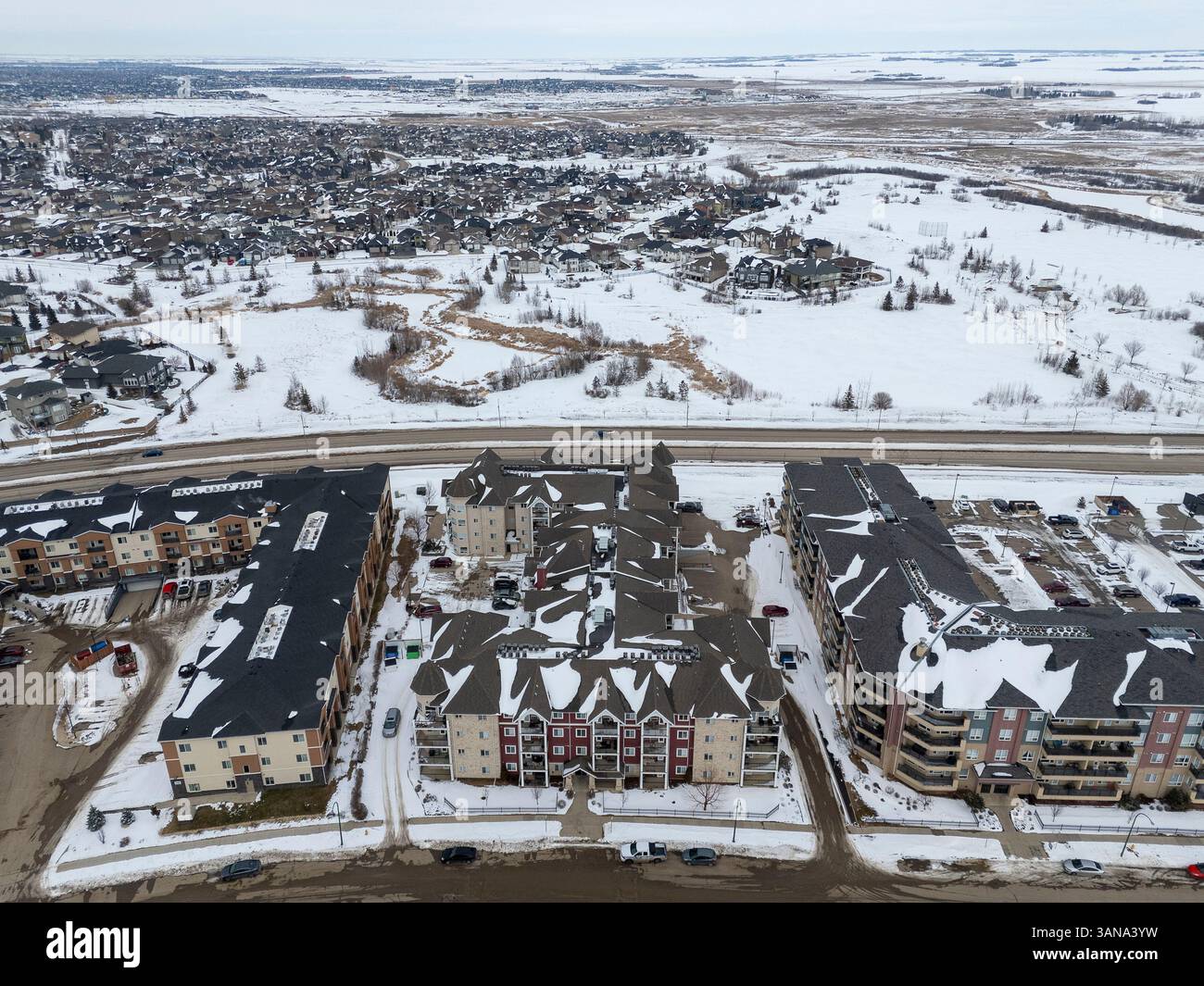 Snowy cityscape with a large apartment complex in the foreground. The ...