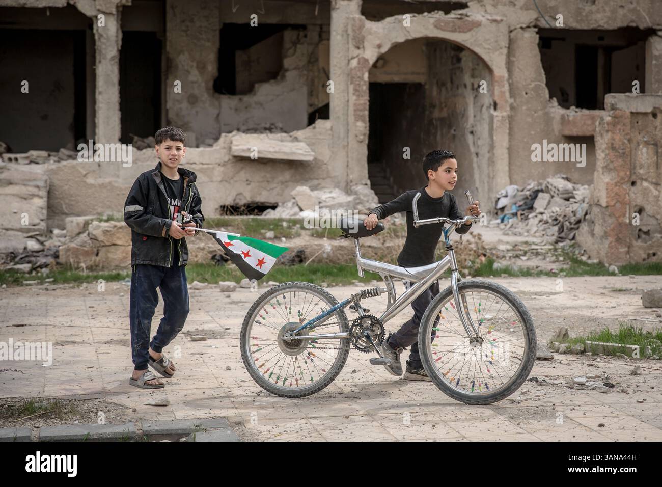 Damascus, Syria. 28th Mar, 2025. Two boys play with a bicycle and a ...