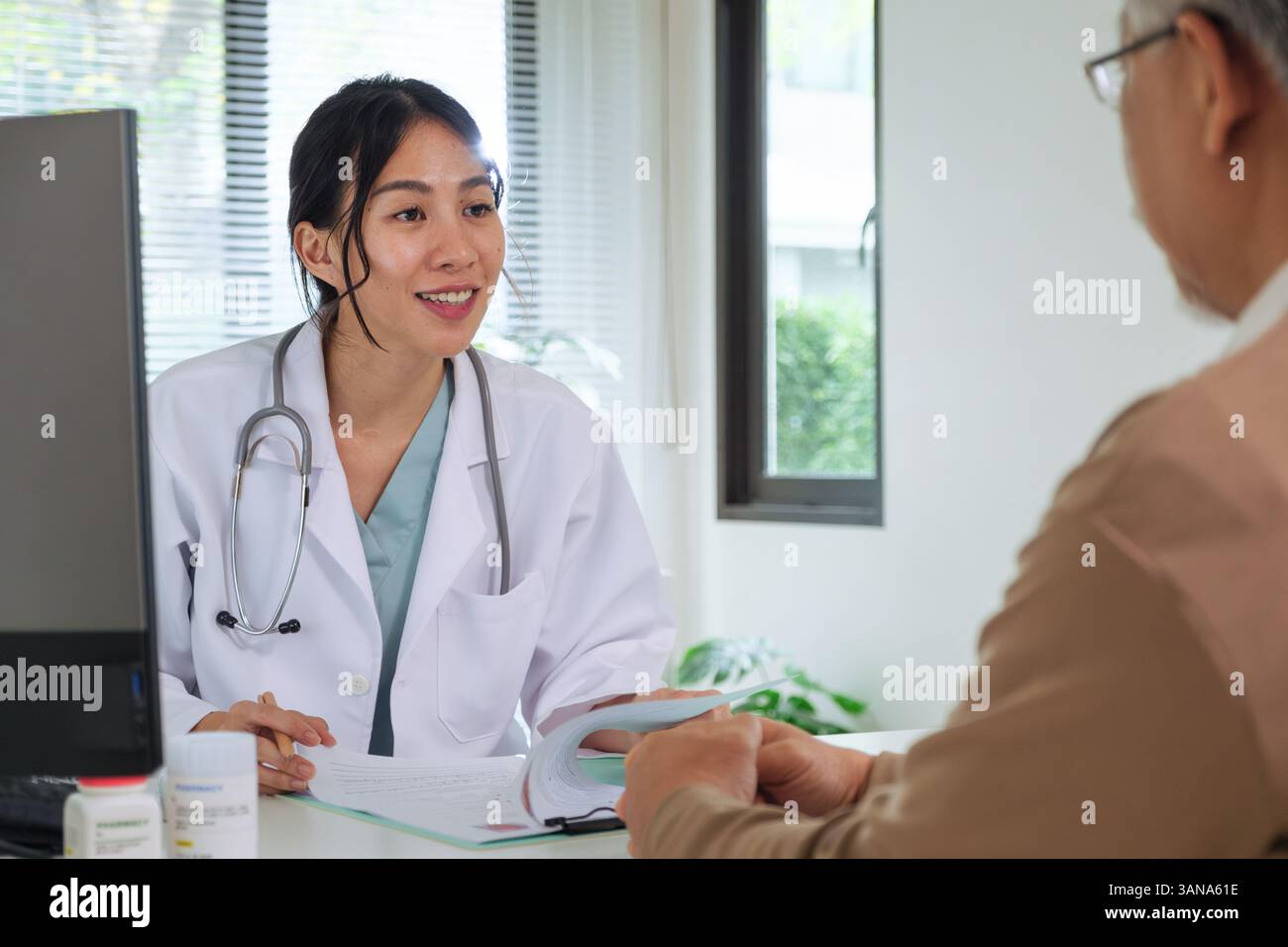 Doctor Reviewing Medical File While Interviewing Elderly Patient at ...