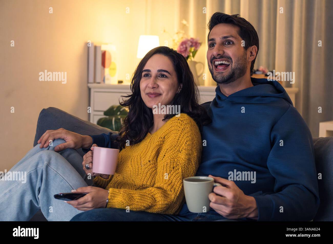 Cozy hispanic couple enjoying a night together wathcing streaming show ...