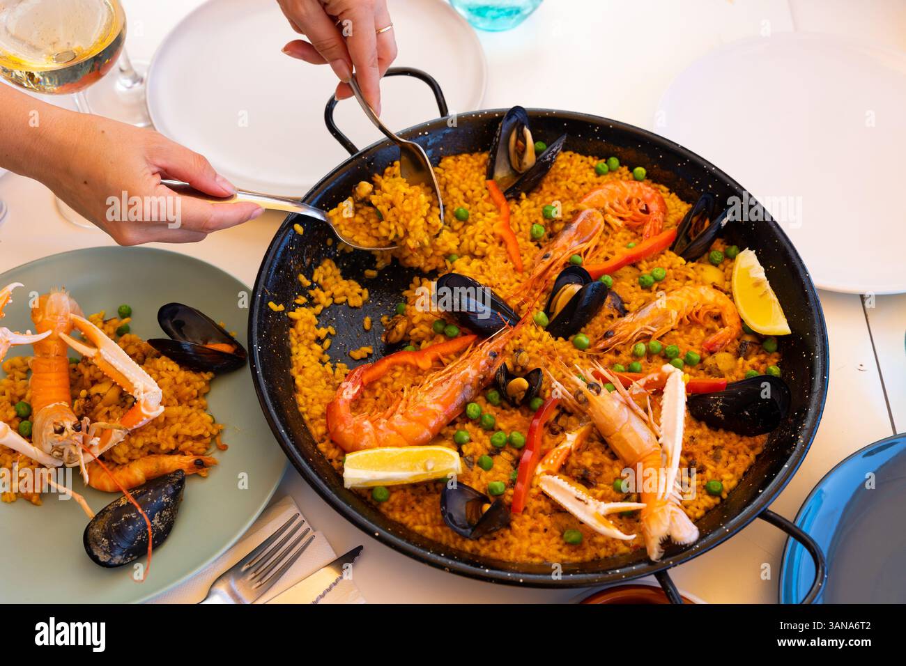 Womens hands lay out sea paella in plates for family dinner Stock Photo ...