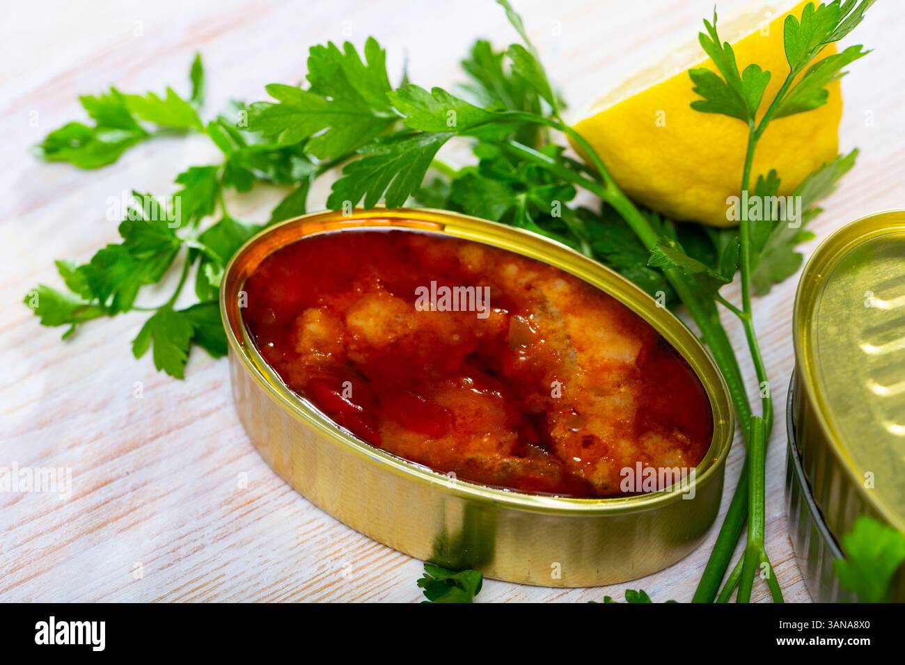 Tinned cod in tomato sauce on background with greens and lemon Stock ...